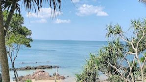Uma praia com águas azul-claras, areal arenoso e vegetação tropical.