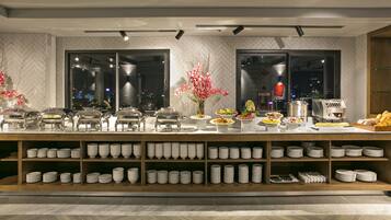 Disposição de buffet com diversos pratos e uma grande variedade de pratos brancos em estantes.