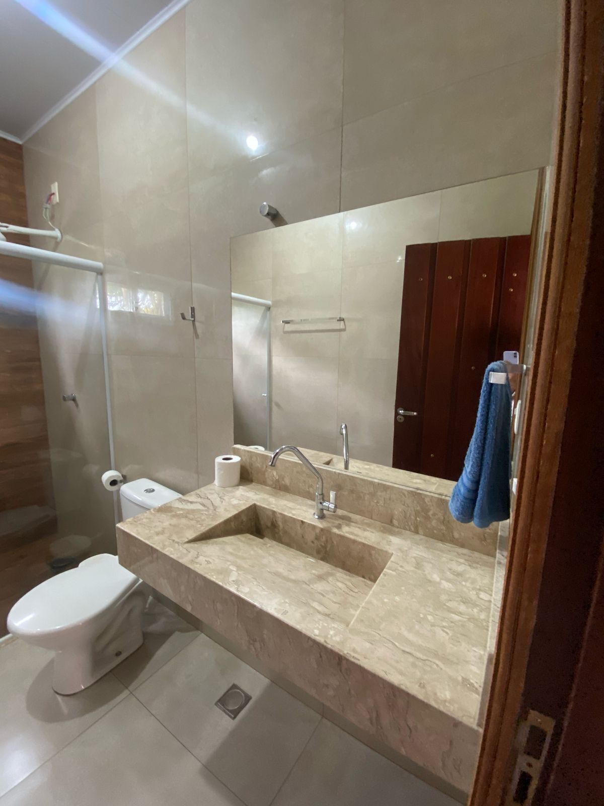 Uma casa de banho moderna com um espelho grande, duas lavatórios, sanita e zona de duche.