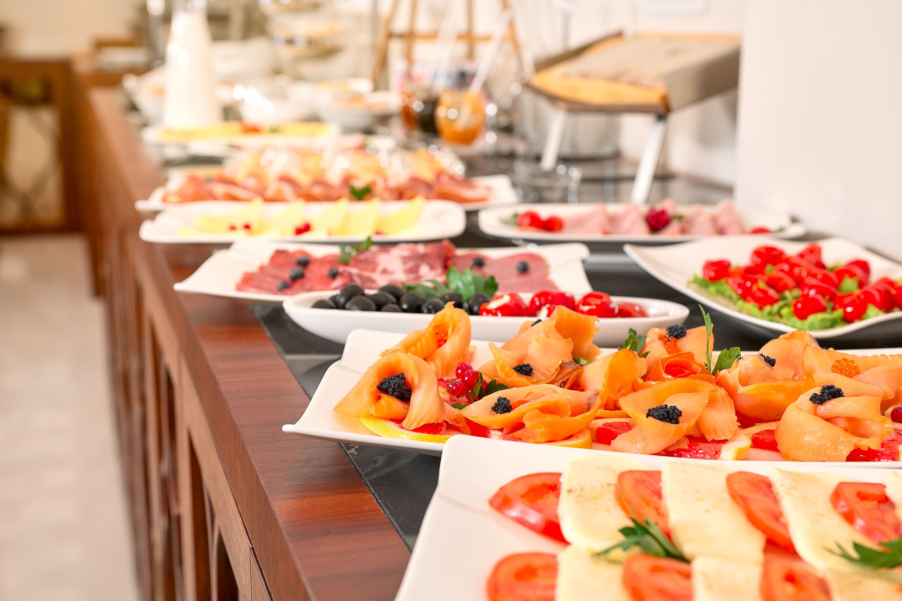 Buffet com diversos alimentos, incluindo salmão defumado, frutas e legumes.