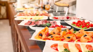 Buffet com diversos alimentos, incluindo salmão defumado, frutas e legumes.