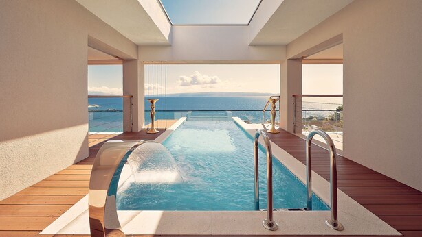 Uma área de piscina com vista desimpedida para o mar, claraboia e deck de madeira.