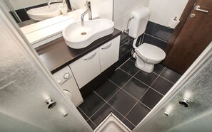Casa de banho moderna com lavatório branco, sanita e zona de duche.