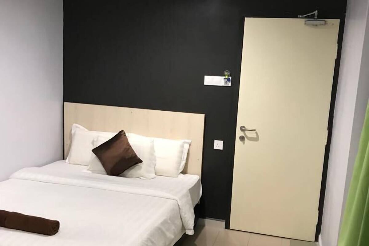 Quarto de hotel com uma cama, porta e luminária no teto.