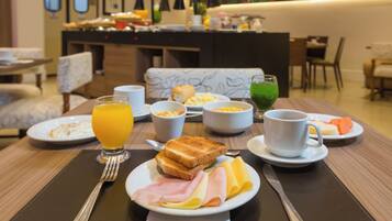 Uma mesa de café da manhã com torradas, presunto, queijo e um copo de suco de laranja.
