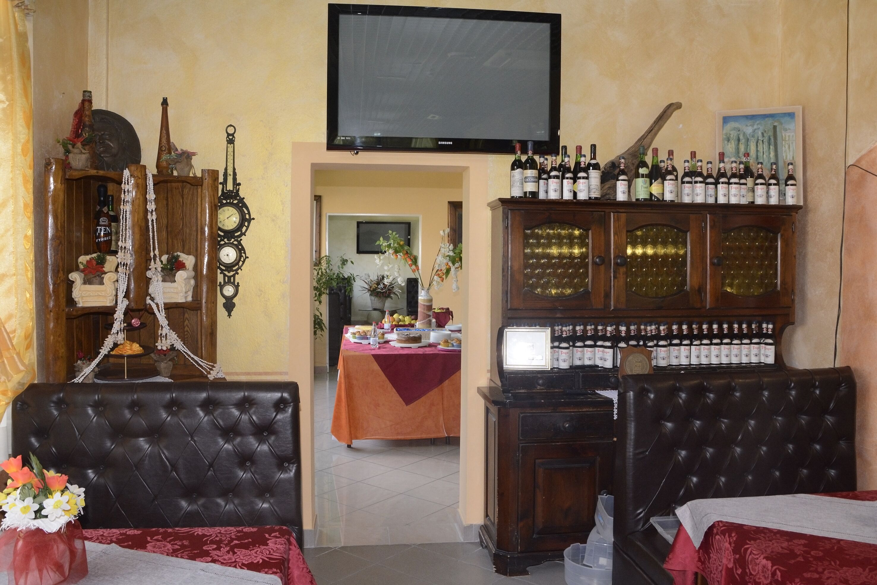 Quarto com televisão, adega, área de jantar com mesa posta para dois e sala de estar com sofá e poltrona.
