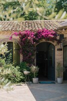 Um edifício com telhado de azulejos, uma entrada e plantas em vasos.