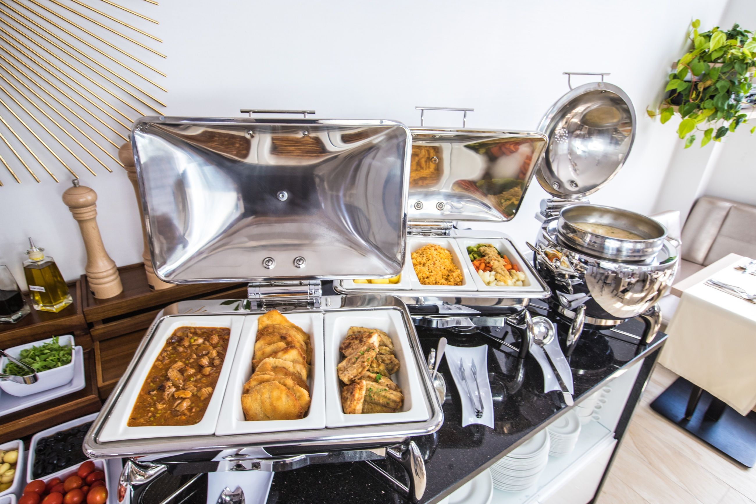 Uma mesa de buffet com diversos alimentos e uma saladeira.