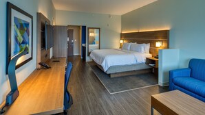 Quarto de hotel moderno com cama, mesa de cabeceira, abajur e escrivaninha com cadeira.