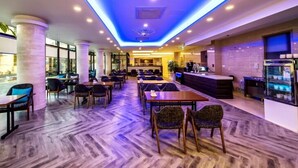 Restaurante moderno com chão em padrão herringbone, mesas e cadeiras de madeira.