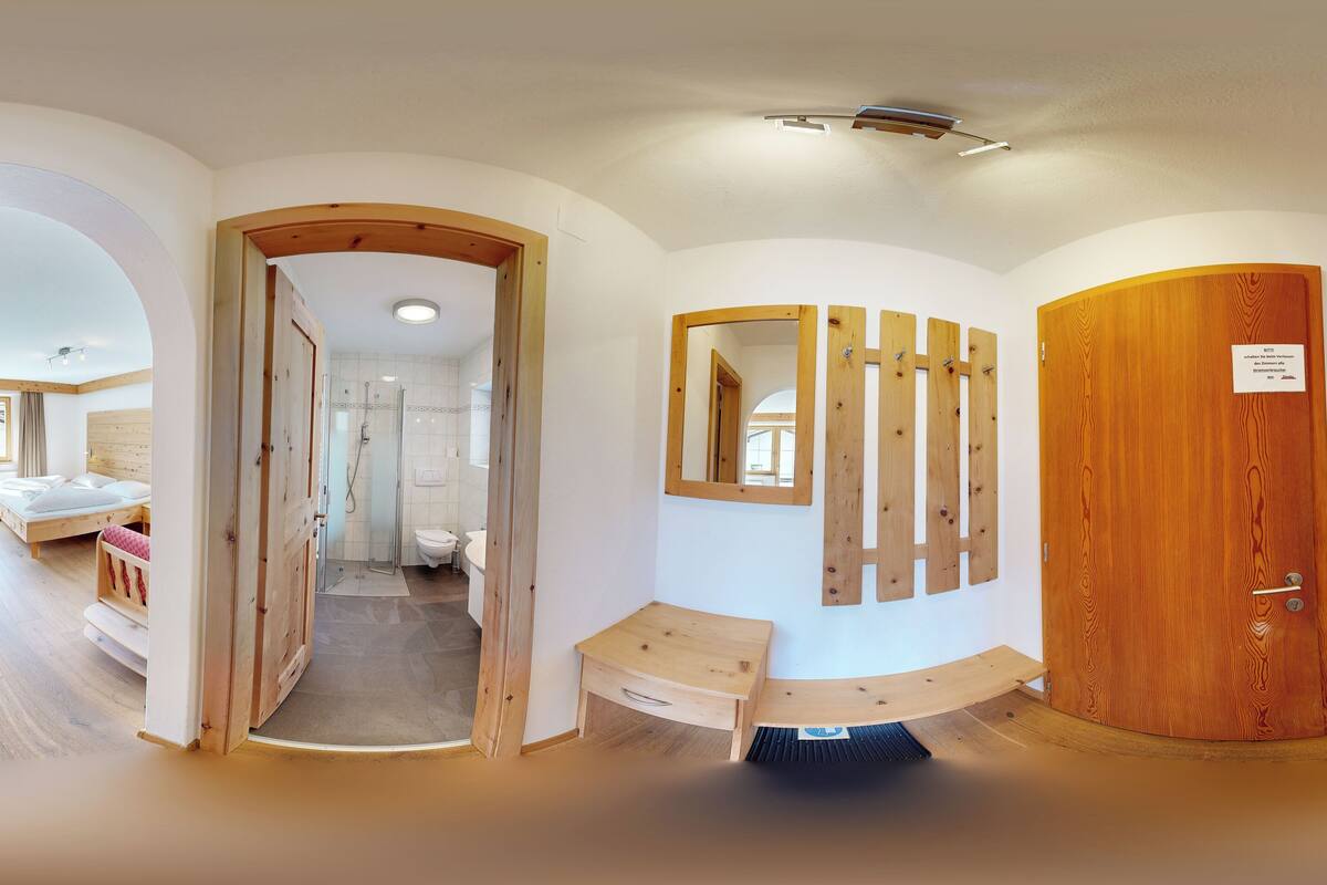 Corredor de hotel com portas de madeira, um banco e um espelho.