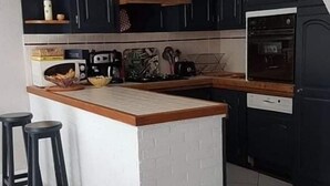 Uma cozinha com ilha central, armários pretos e piso de azulejos brancos.