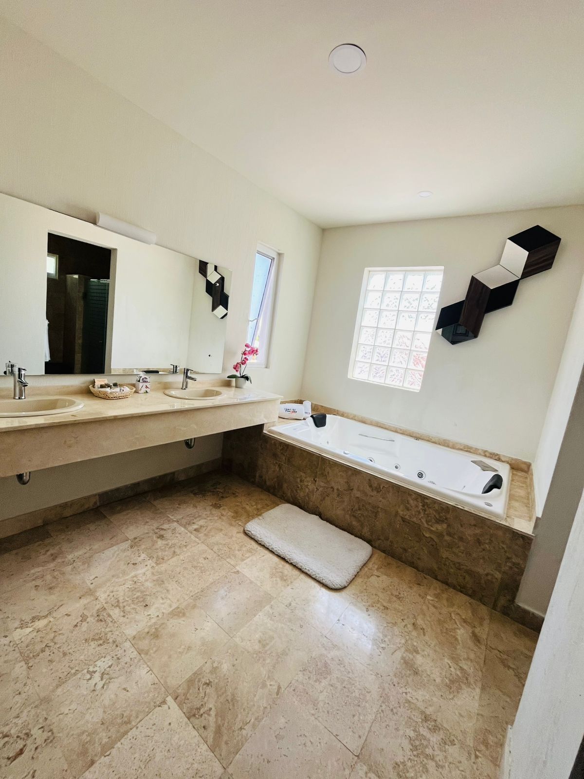 Uma casa de banho moderna com duas bacias, um espelho grande, uma janela e uma banheira integrada.