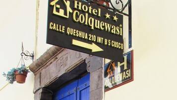 Placa de hotel com o nome 'Hotel Colquewasi' e uma seta indicando Calle Queshua 210 Int B5 Cusco.