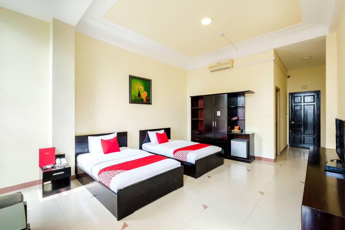 Quarto de hotel com duas camas, uma escrivaninha, um guarda-roupa e uma televisão.