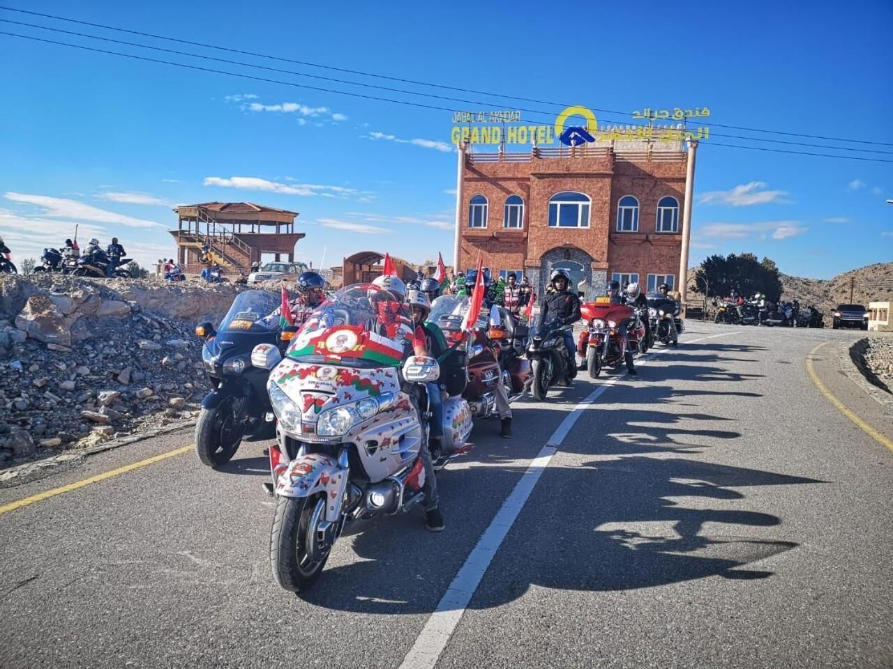 Uma fileira de motocicletas estacionadas em frente a um edifício com uma placa que diz 'Grand Hotel'.