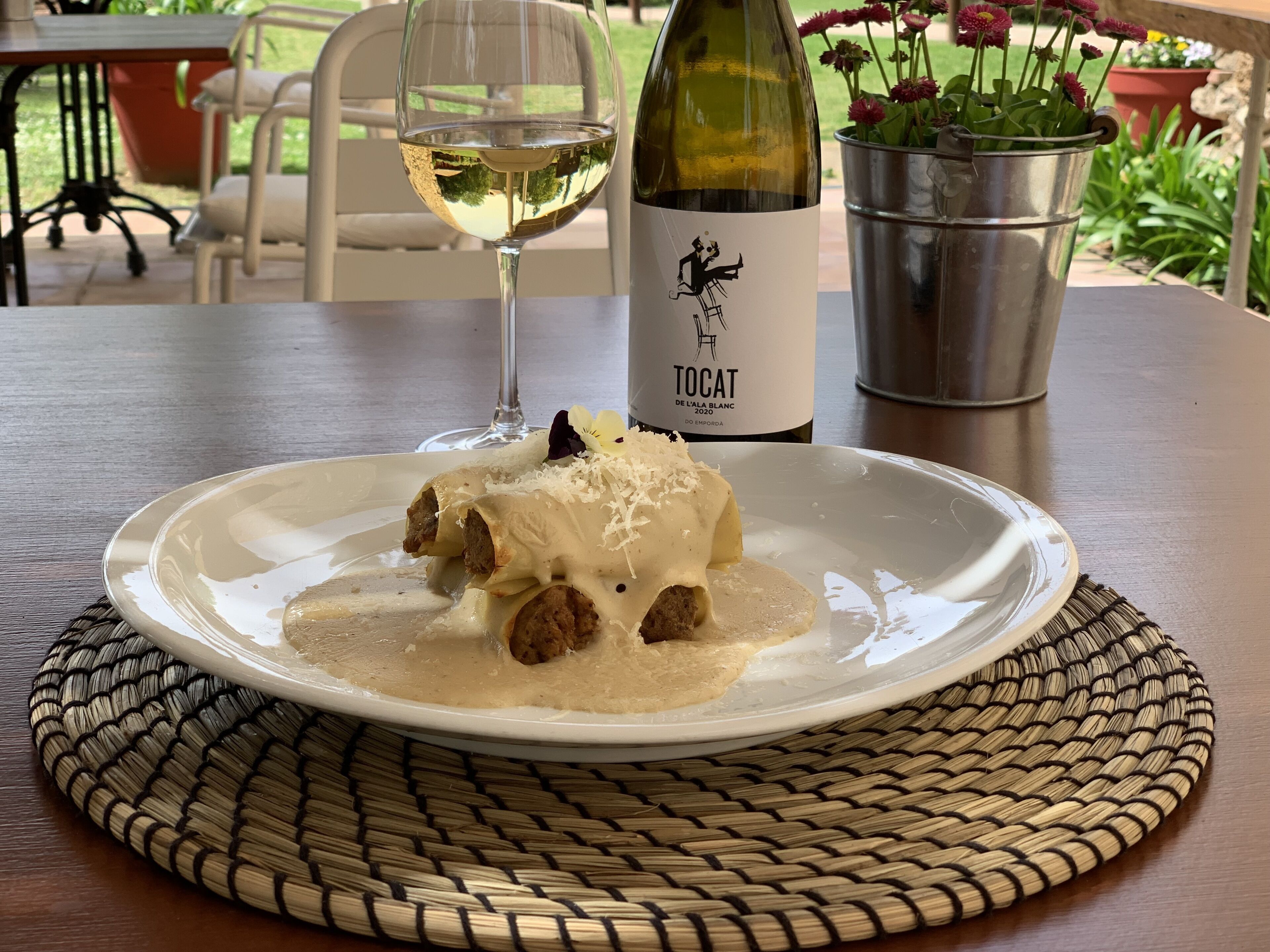 Um prato de comida com uma garrafa de vinho e um balde de metal com flores.