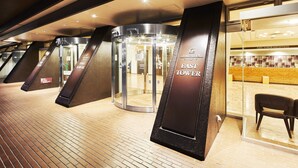 Entrada de hotel com portas giratórias e uma área de recepção.