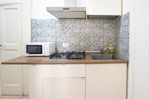 Uma cozinha com micro-ondas, fogão a gás e pia.