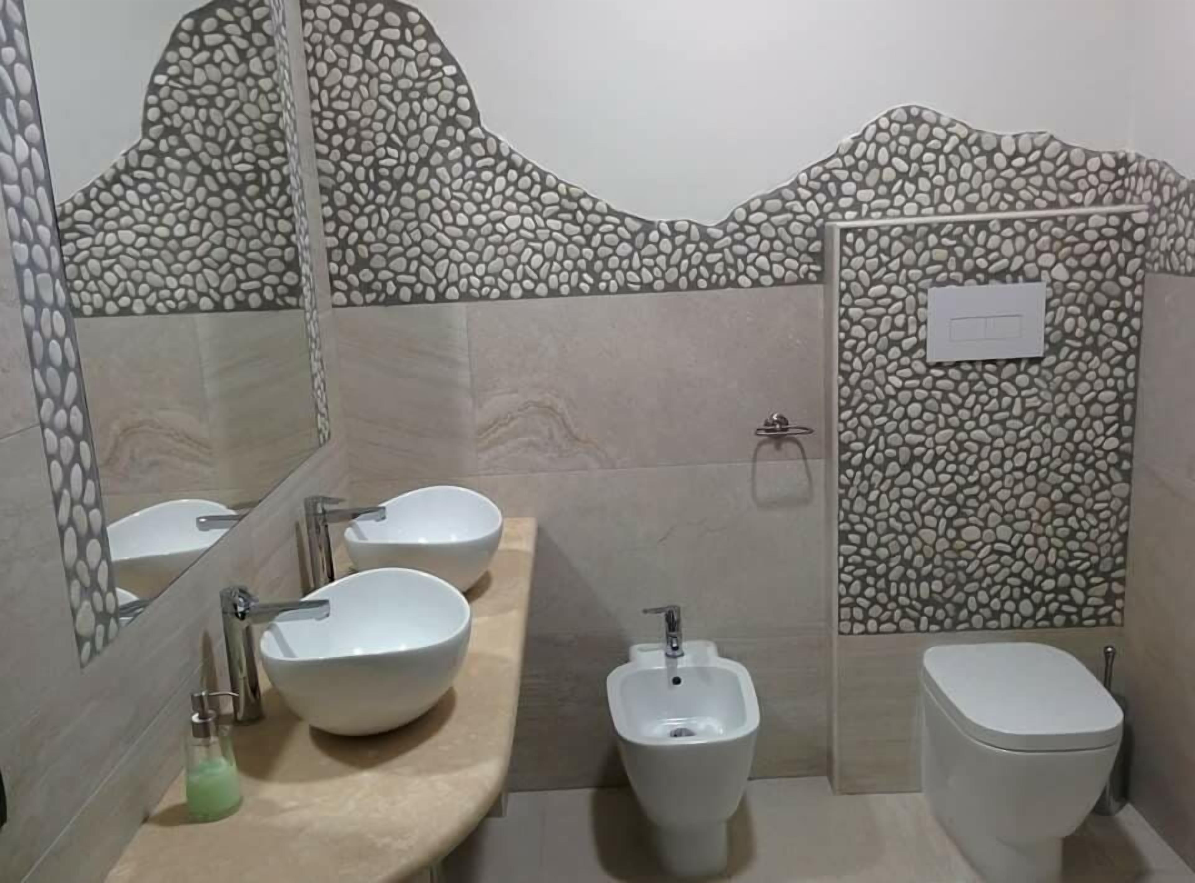 Casa de banho com duas pias, um bidé e uma sanita.