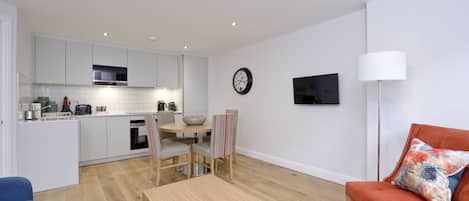 Uma sala de estar moderna com um sofá, uma mesa de centro e um espaço de jantar com cadeiras e uma mesa.