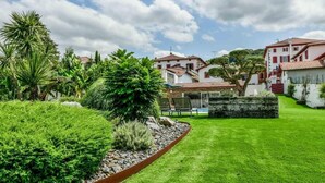 Um jardim bem cuidado, com diversas plantas e um elemento decorativo de pedra.