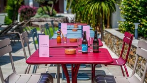 Uma mesa vermelha com um cardápio, garrafas de vinho e uma vela.