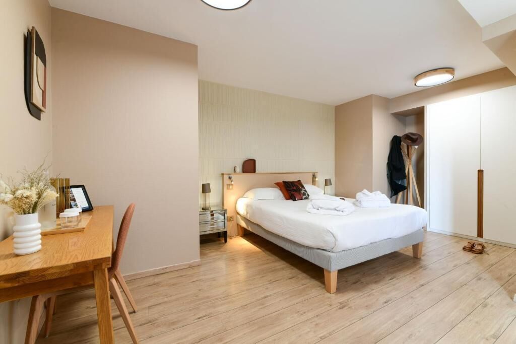 Quarto com cama, mesas de cabeceira, escrivaninha e cadeira.