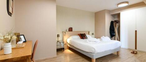 Quarto com cama, mesas de cabeceira, escrivaninha e cadeira.