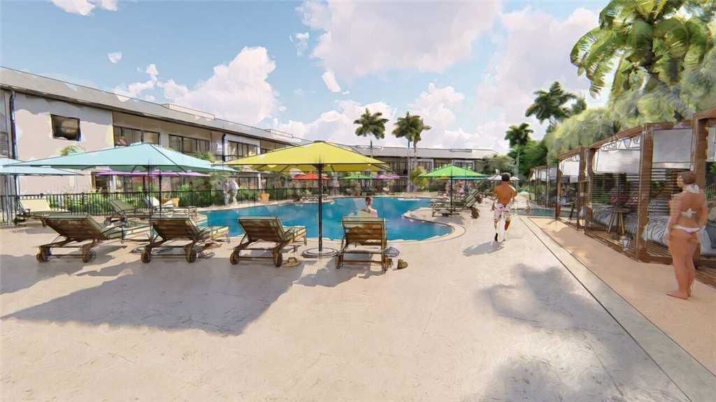 Uma área de piscina com espreguiçadeiras e guarda-sóis, cercada por um edifício com telhado plano e janelas.