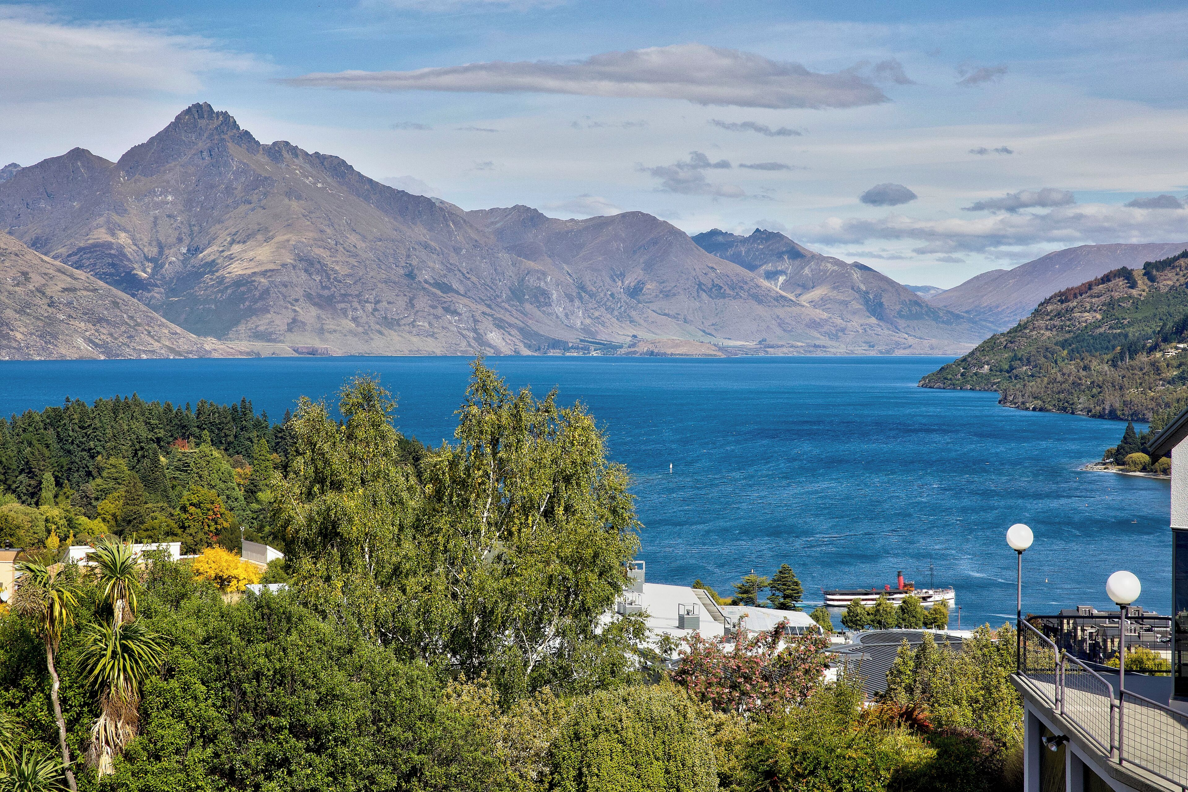 Paisagem montanhosa com um lago, edifícios e árvores.