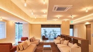Um lobby de hotel moderno com sofás, uma mesa de centro e vista para o exterior.