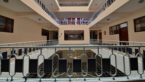 Um átrio de vários níveis com um espaço aberto central, corrimãos e piso em grade.