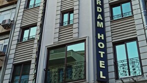 Um edifício de hotel com vários andares e uma placa grande com a inscrição 'NLMAMSTERDAM HOTEL'.