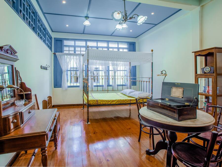 Um quarto com uma cama, uma escrivaninha, uma cadeira e uma estante de livros.