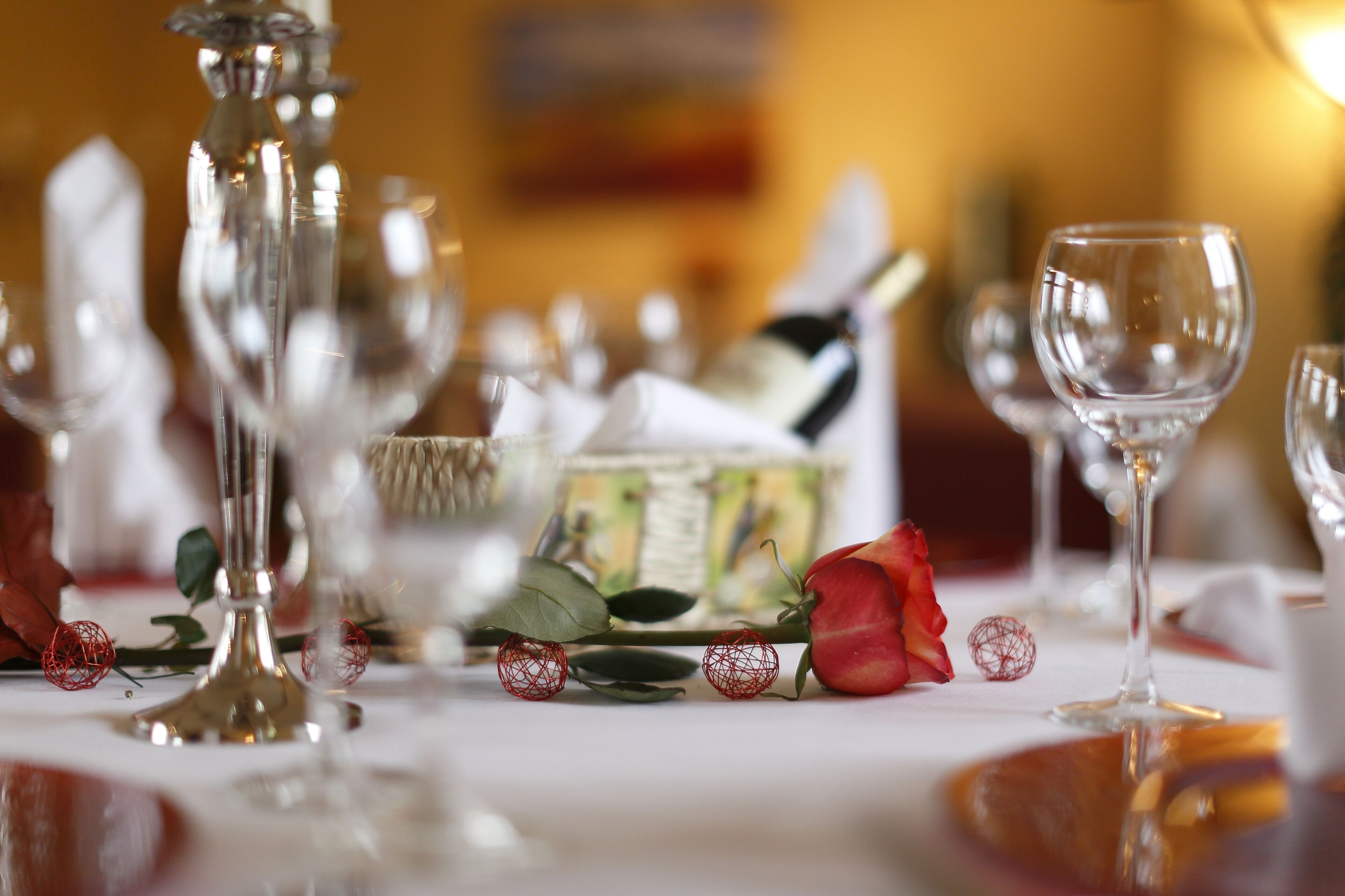 Mesa posta com taças de vinho, uma rosa e elementos decorativos.