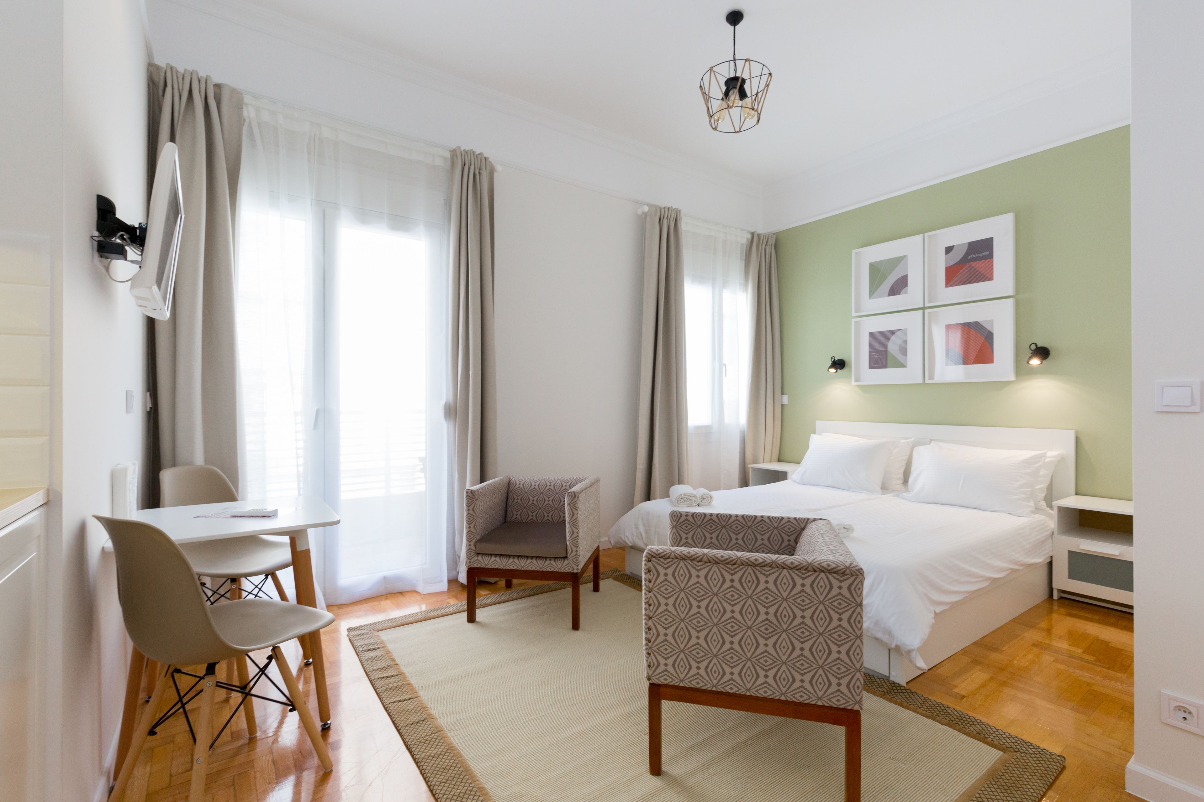 Quarto de hotel com uma cama, duas cadeiras, uma mesa e uma escrivaninha.