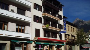 Um hotel com vários andares, varandas e um restaurante no nível térreo.