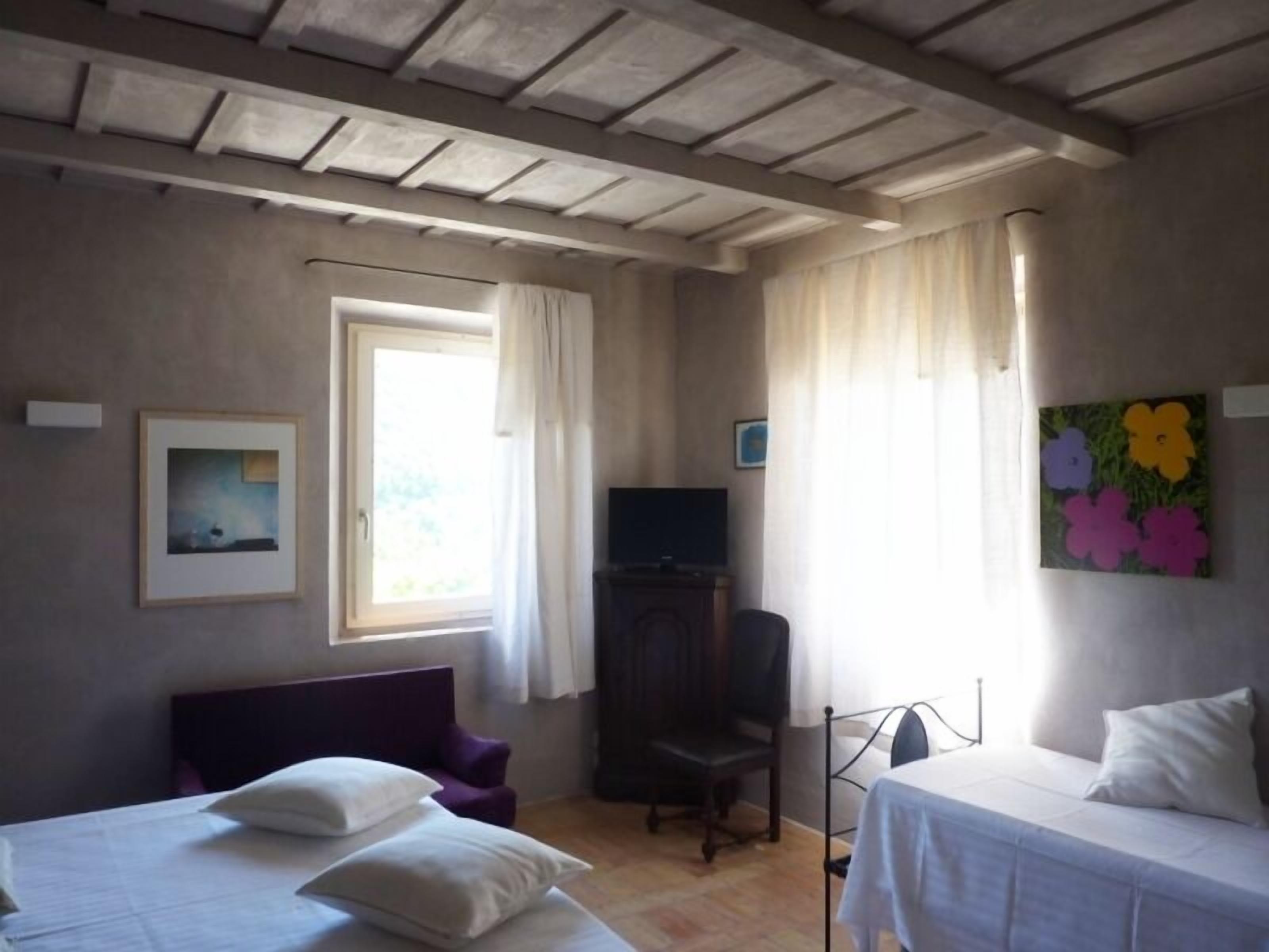 Quarto com duas camas, televisão, janela com cortinas e um quadro na parede.