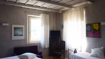 Quarto com duas camas, televisão, janela com cortinas e um quadro na parede.