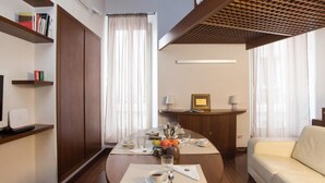 Uma sala de jantar moderna com uma mesa redonda posta para dois, um sofá e uma estante.