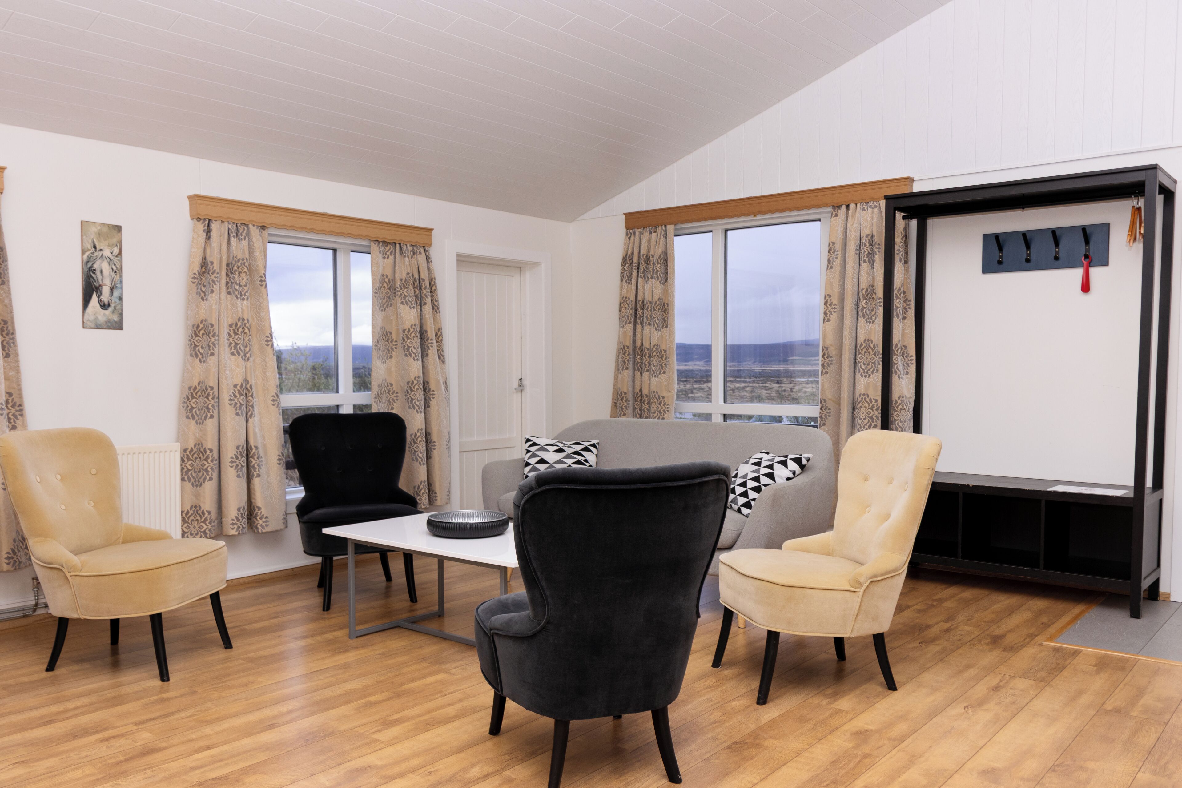 Sala de estar com sofá, duas poltronas, mesa de centro e painel para TV com televisão montada.
