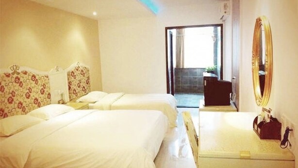 Quarto de hotel com duas camas, uma cômoda, um espelho e vista para o exterior.