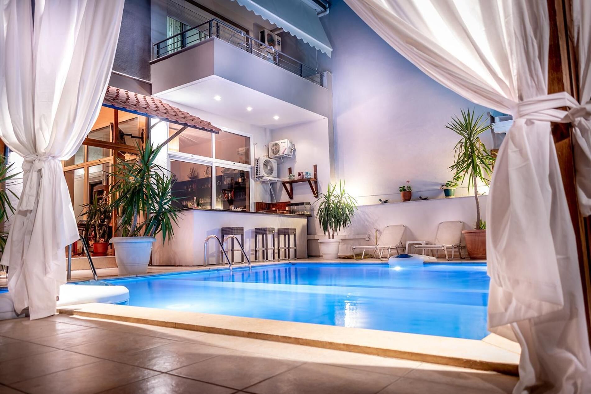 Piscina interior com área de bar, assentos e plantas em vasos.