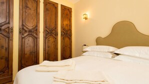 Quarto de hotel com cama, roupa de cama branca e armários de madeira.