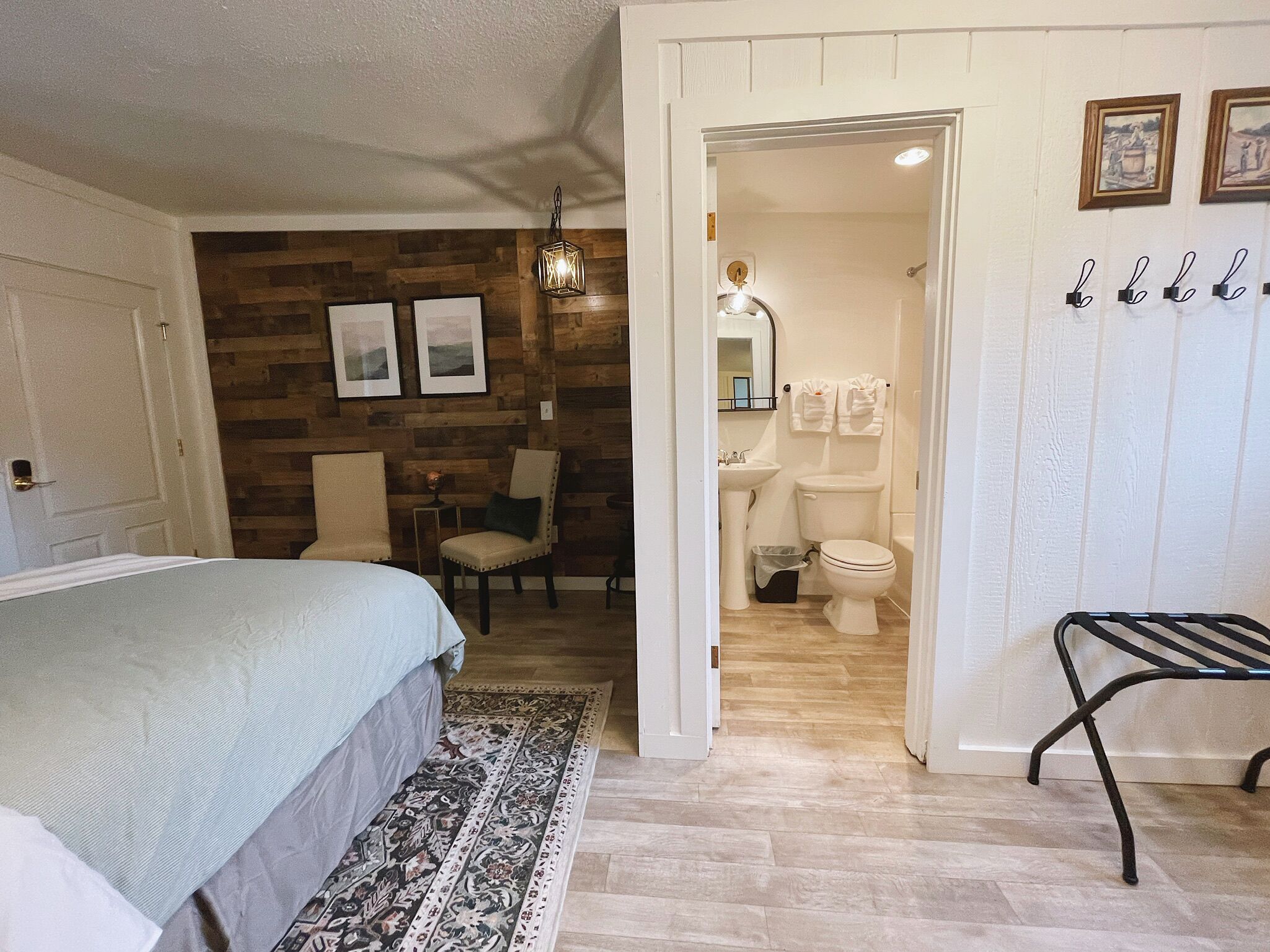 Um quarto com cama, uma cadeira, uma mesinha e um tapete.