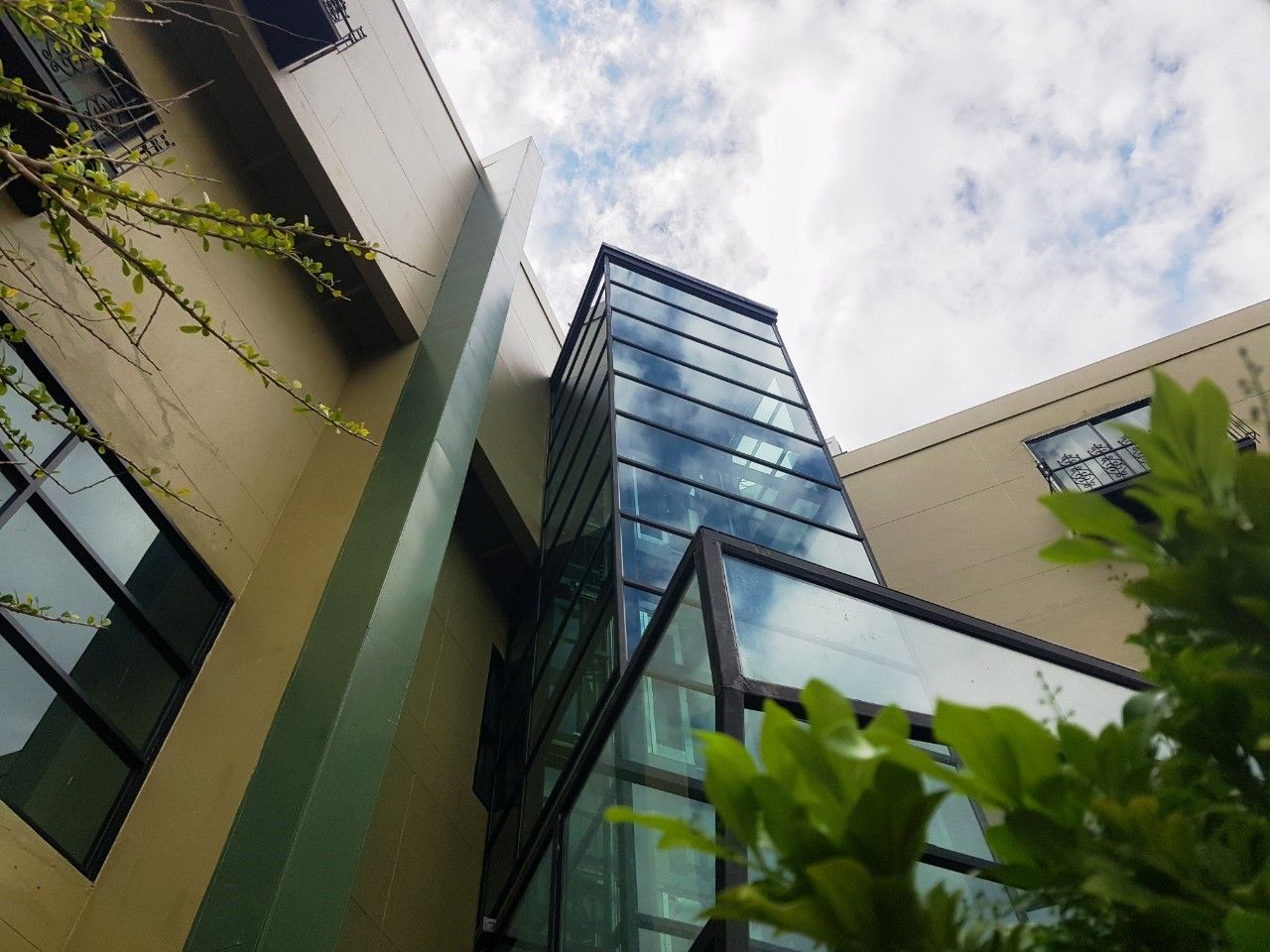 Um edifício moderno com fachada de vidro e uma parede de destaque verde.