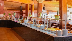 Uma área de buffet com diversos alimentos e frutas decorativas.
