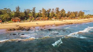 Uma praia com palafitas e uma margem arenosa.