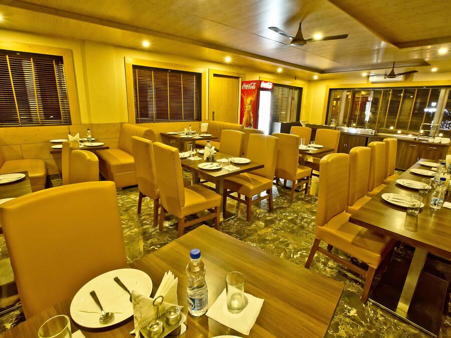 Um restaurante com cabines e mesas, cada uma disposta com pratos, talheres e garrafas de água.